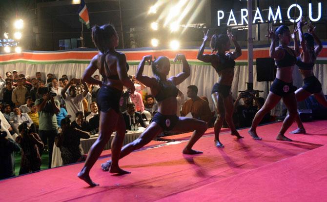 Female bodybuilders showcase their muscle power to the judges during ...